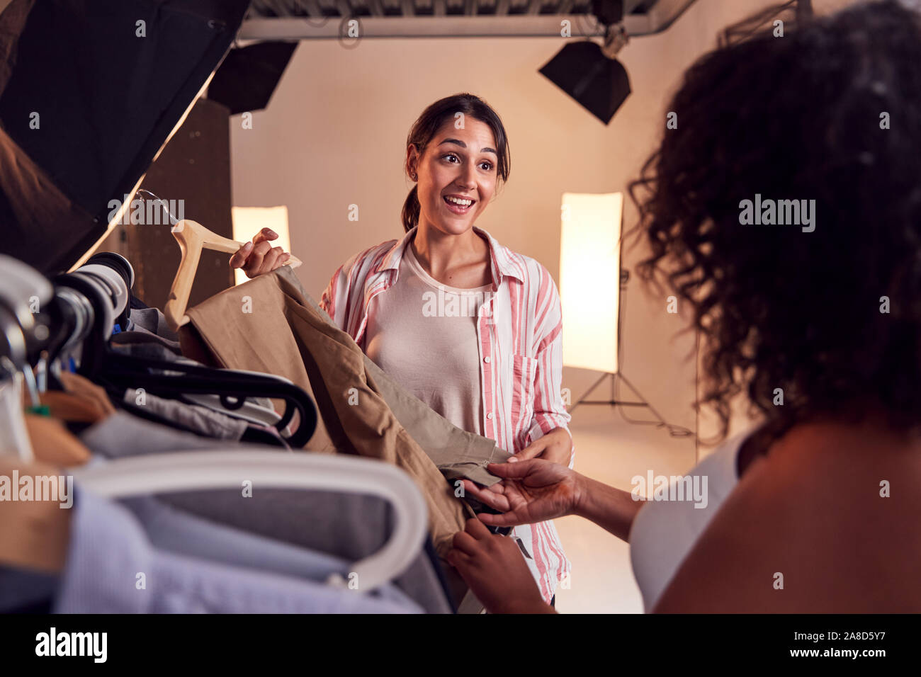 Stylist Discussing Wardrobe With Female Photographer On Fashion Shoot ...