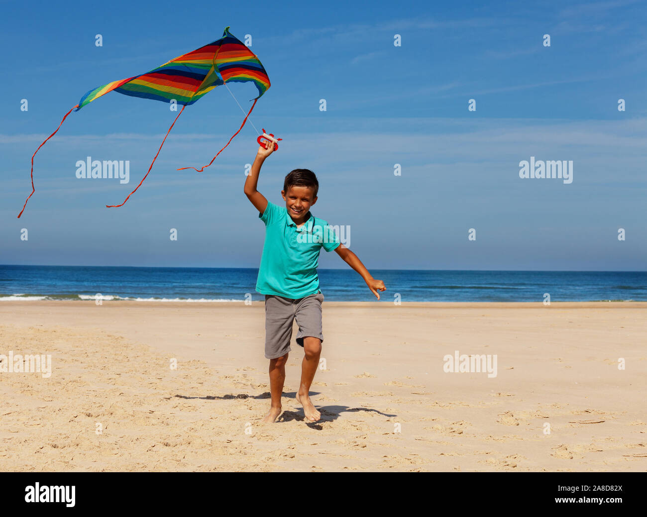 Happy little boy run with color stripped kite Stock Photo - Alamy