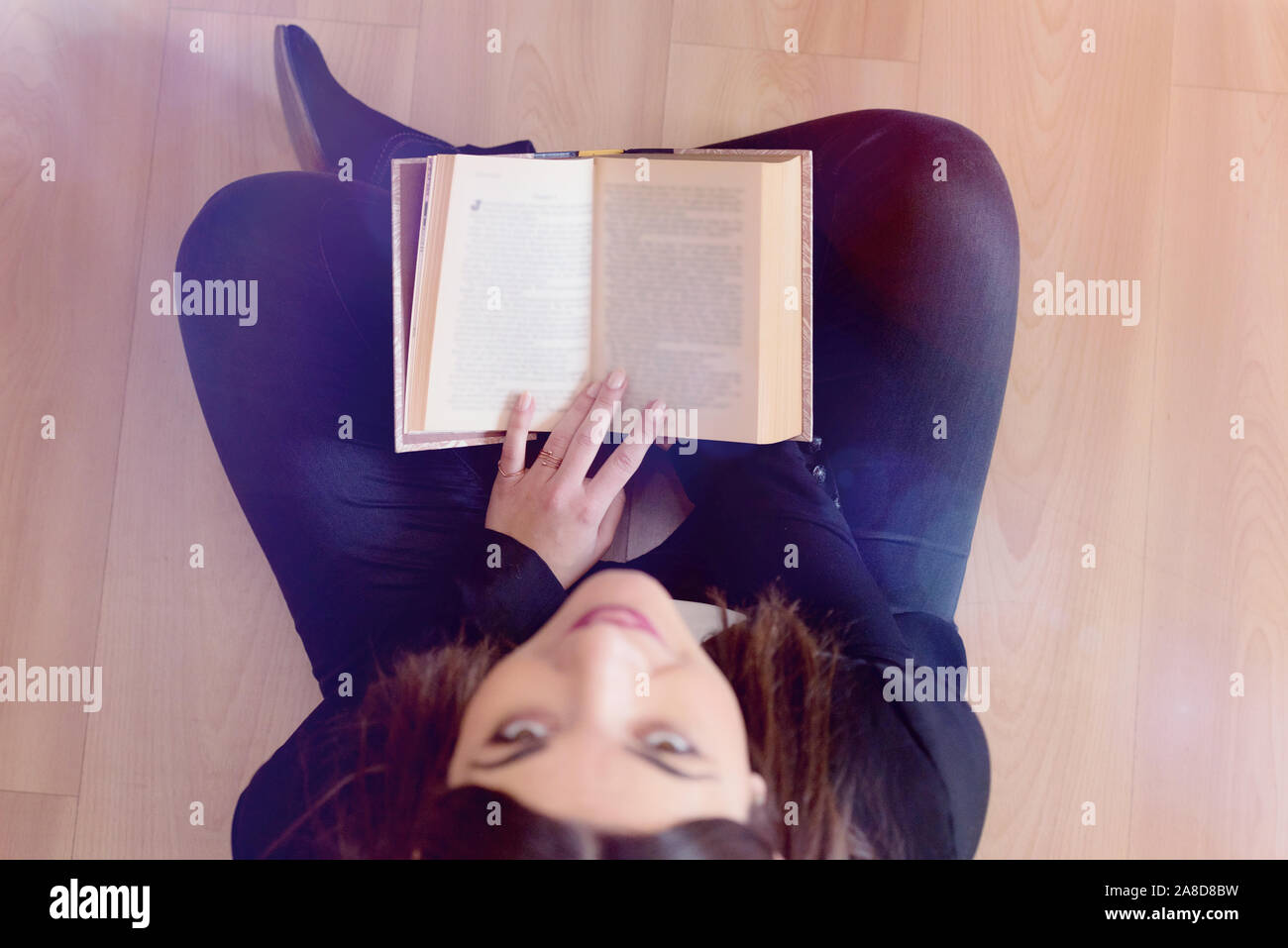 Adult young Female student reading a book at library, sitting on the ...