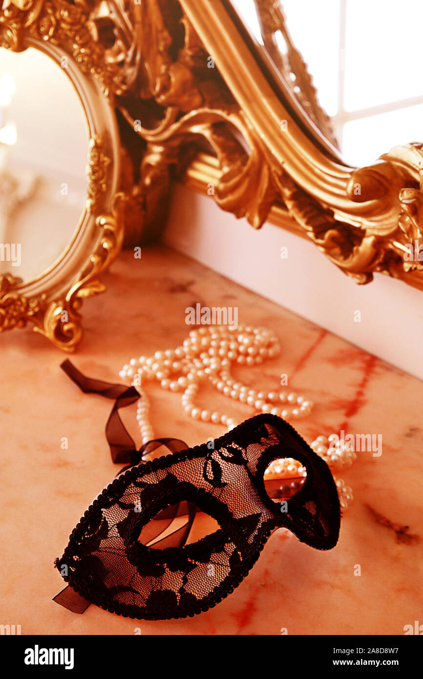 Black lace masquerade mask on table. Female Boudoir, pearl necklace ...