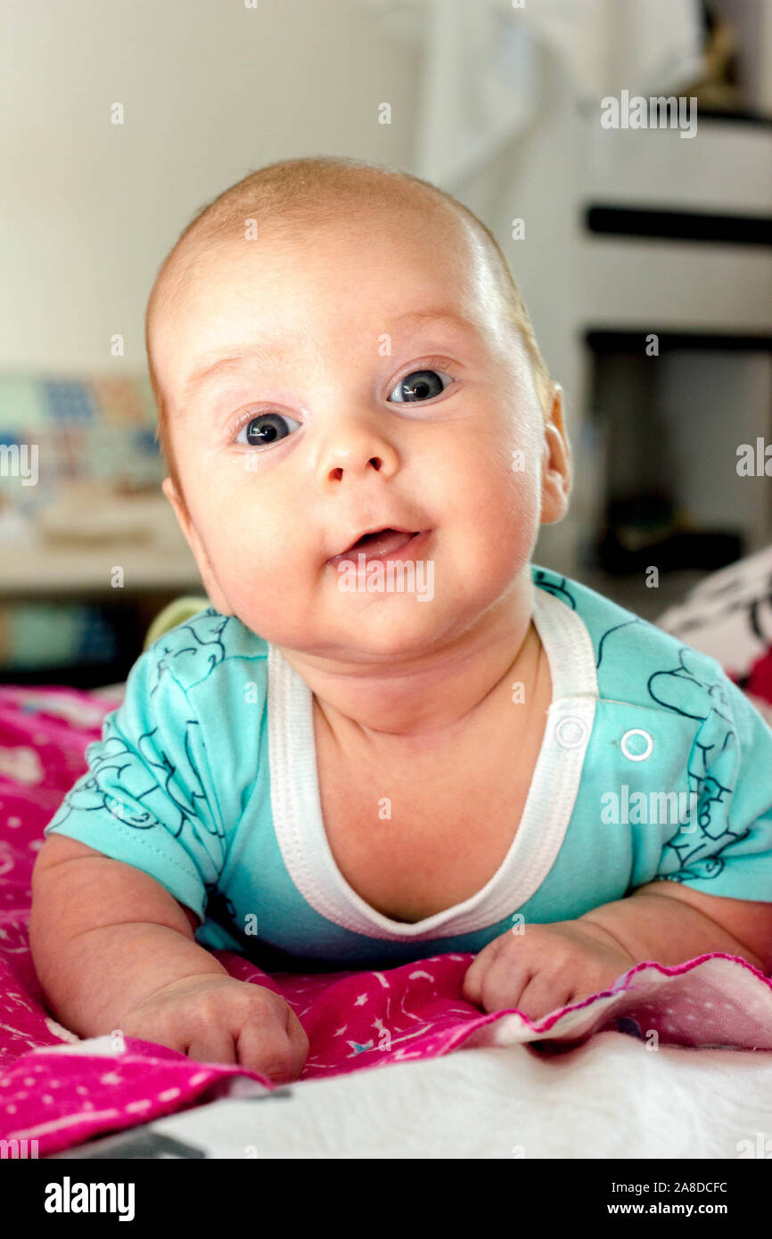 The charming child in blue smiles and lies on a stomach Stock Photo - Alamy