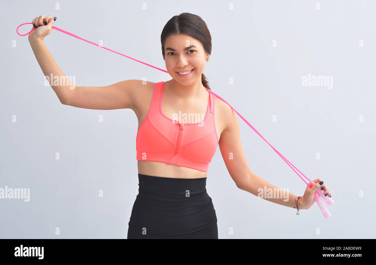 Sporty young asian girl holding jump role and doing exercise on gray ...