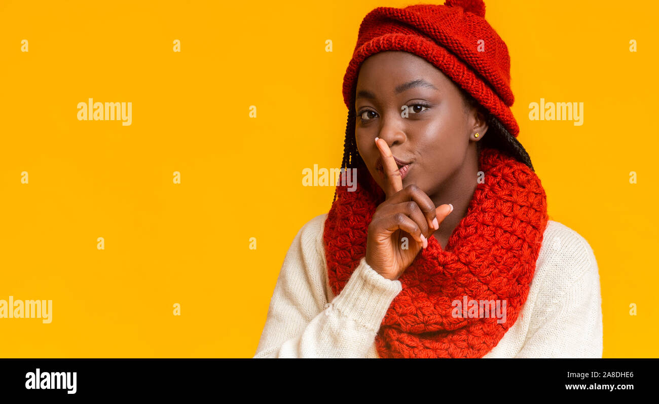 Pretty cheerful silent black girl making hush gesture Stock Photo - Alamy