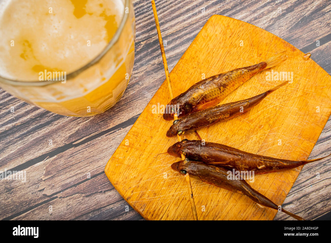 Dried mullet on a wooden Board with a mug of beer on the table. Fish ...