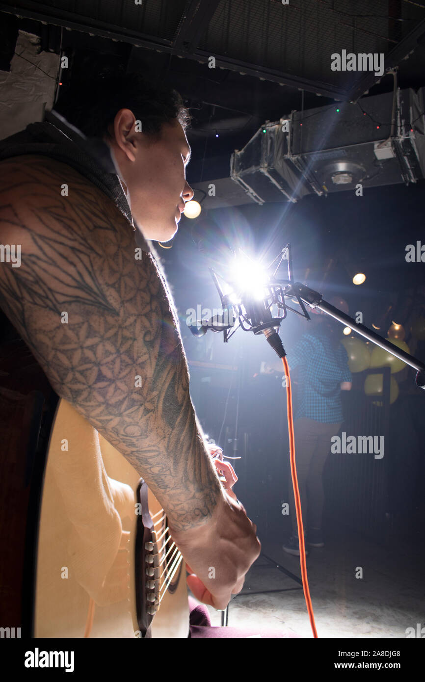 Man playing guitar, singing into a microphone Stock Photo - Alamy