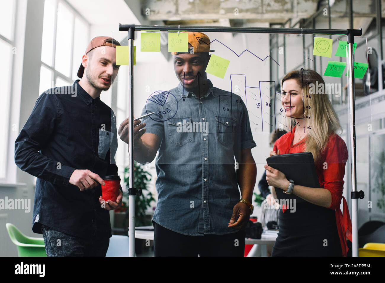 Three young Business people meeting at office and use post it notes to ...