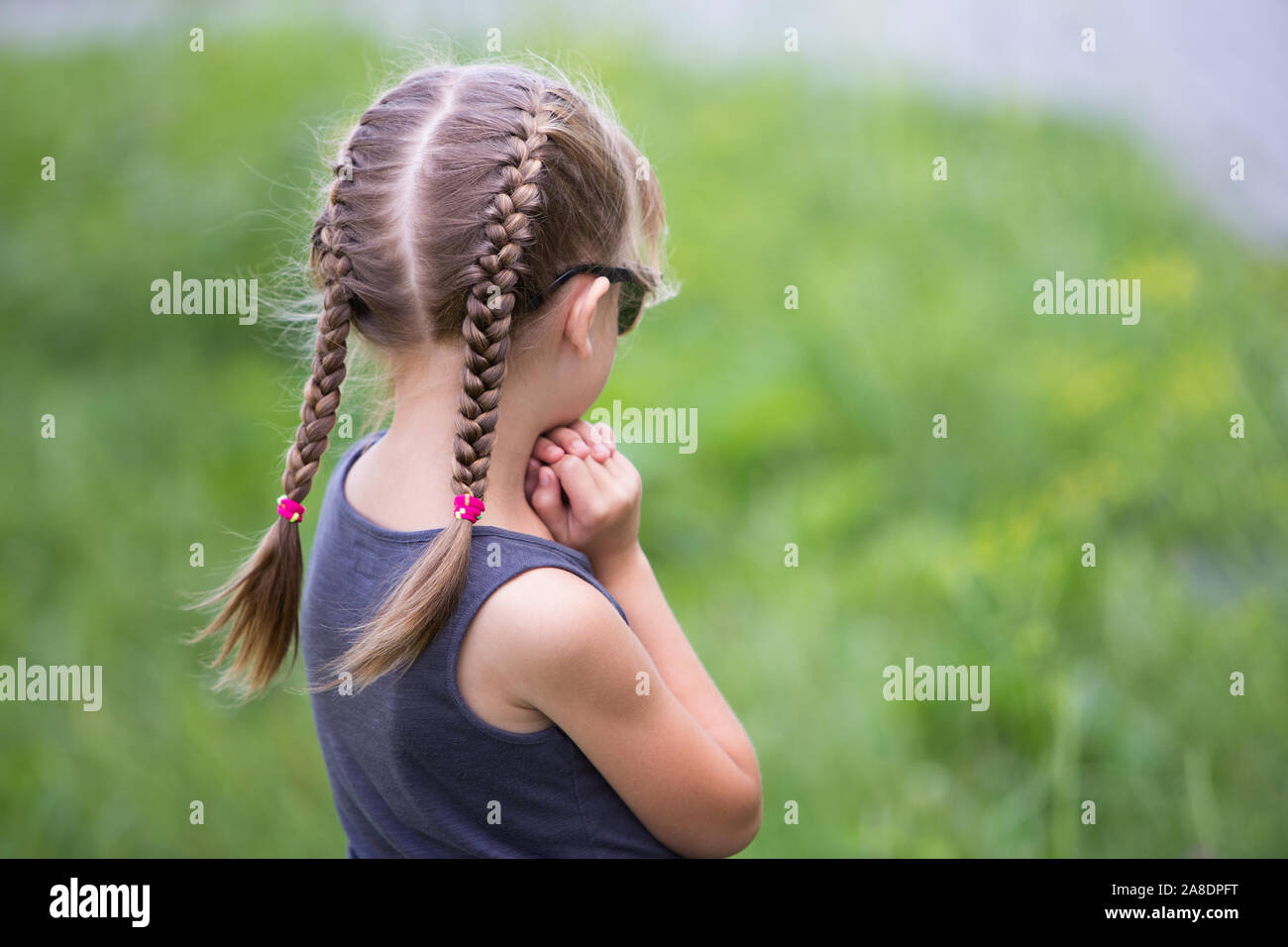 Portrait of pretty child girl with braids in hair outdoors in summer ...