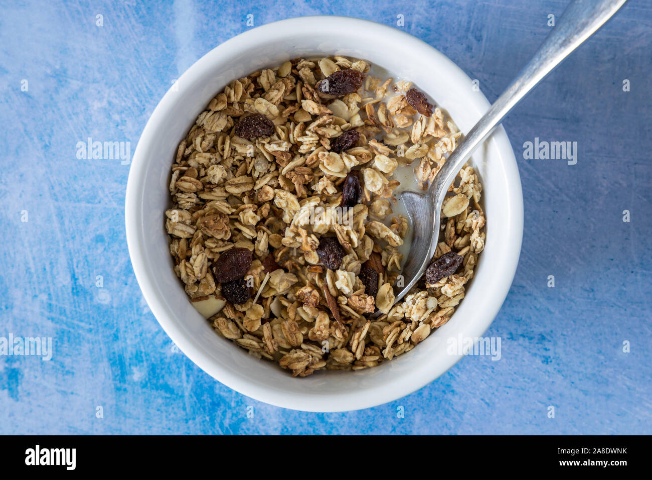 Breakfast granola cereal bowl with fruit and spoon on minimal blue food ...