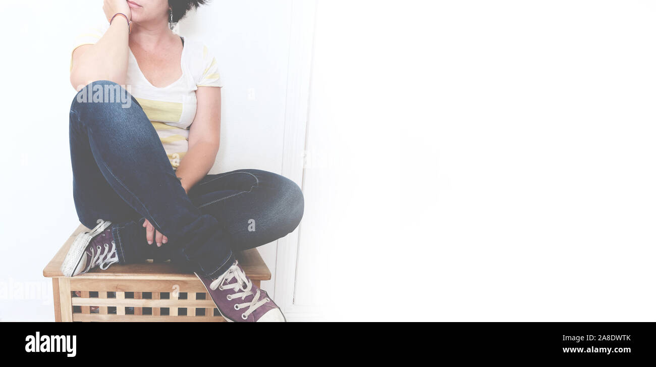 sad woman in jeans sitting thinking Stock Photo - Alamy