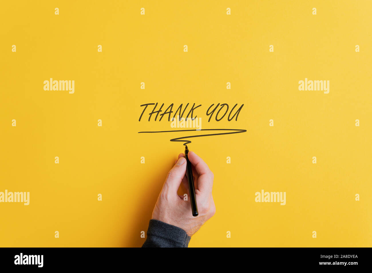 Male hand writing a Thank you sign with black marker on a yellow ...