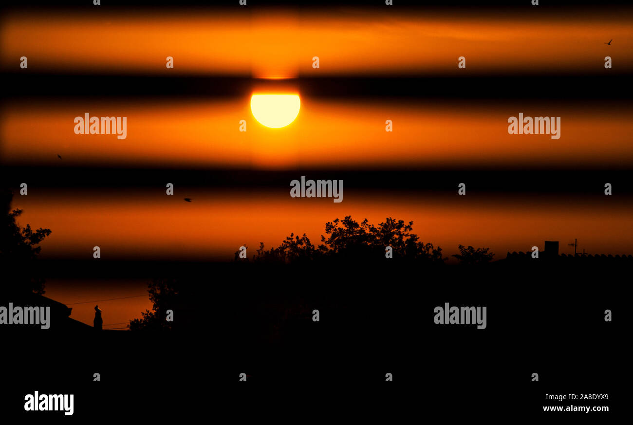 Sunset seen from inside the house. The shutters create a suggestive ...