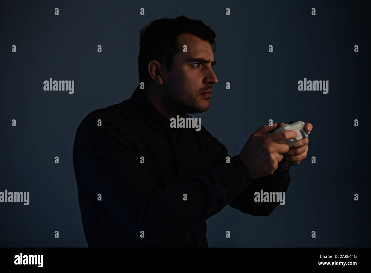 Serious young man playing video games isolated over grey background ...