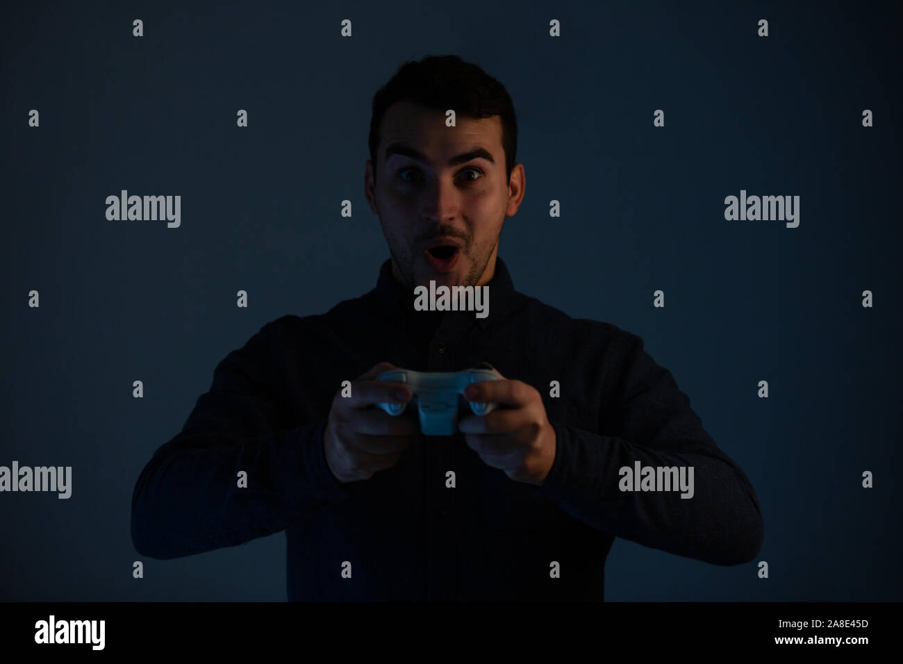 Joyful young man playing video games isolated on grey background ...