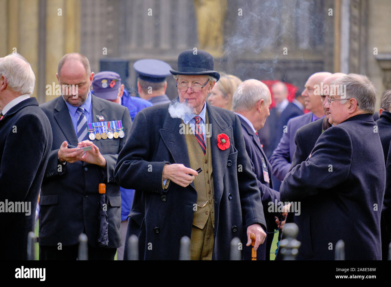 Distinguished gentleman with a suit and a bowler hat smoking a pipe ...