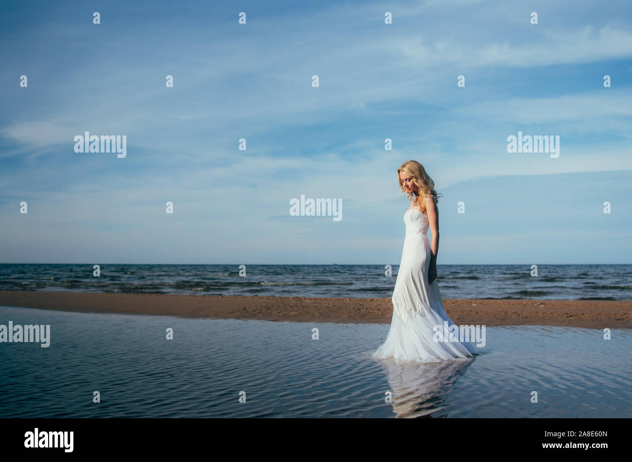 Portrait of young blond bride walking among the water, looking down ...