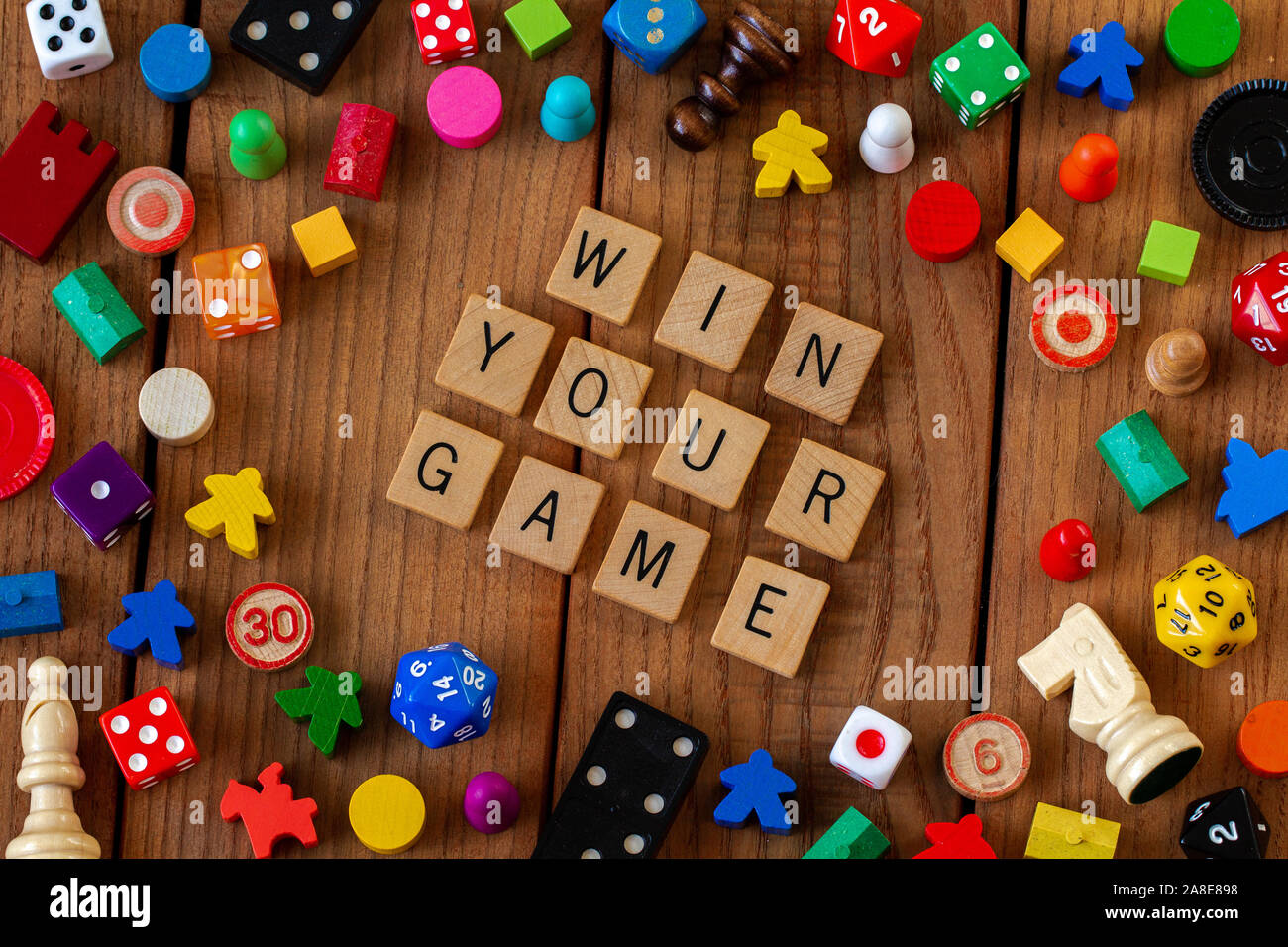 "Win Your Game" spelled out in wooden letter tiles. Surrounded by dice ...