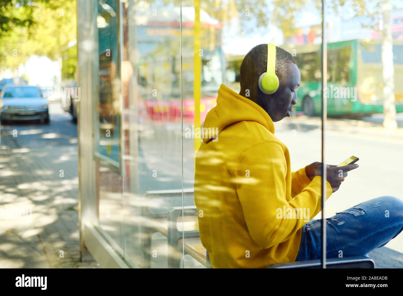 African Young Man Listening To Music At Bus Stop Stock Photo - Alamy