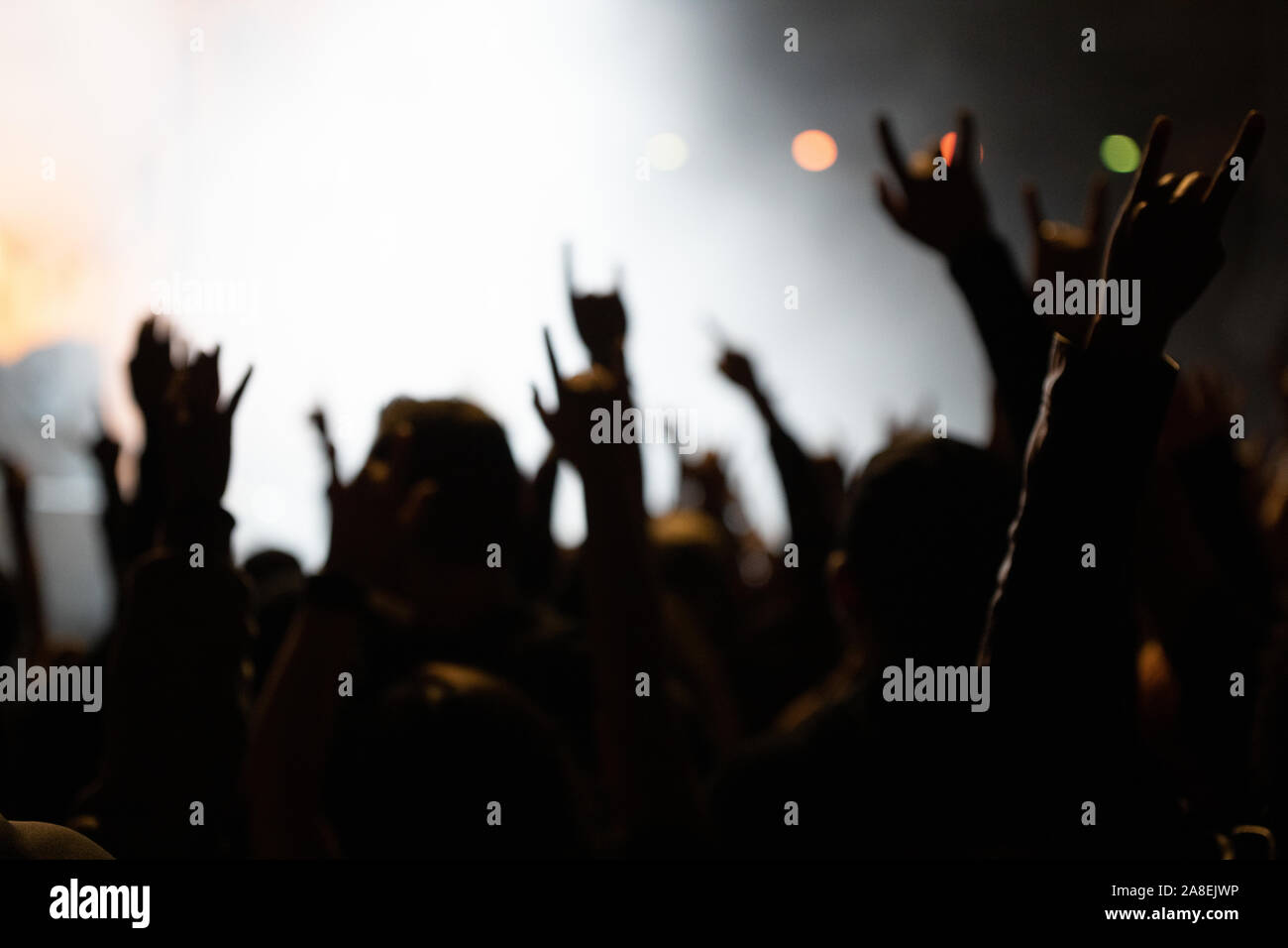 Out of focus crowd at a concert with a bright stage. Fans with their ...