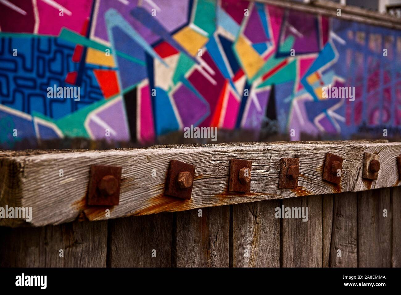 Weathered wooden construction on pebble beach Rusting bolts graffiti on ...