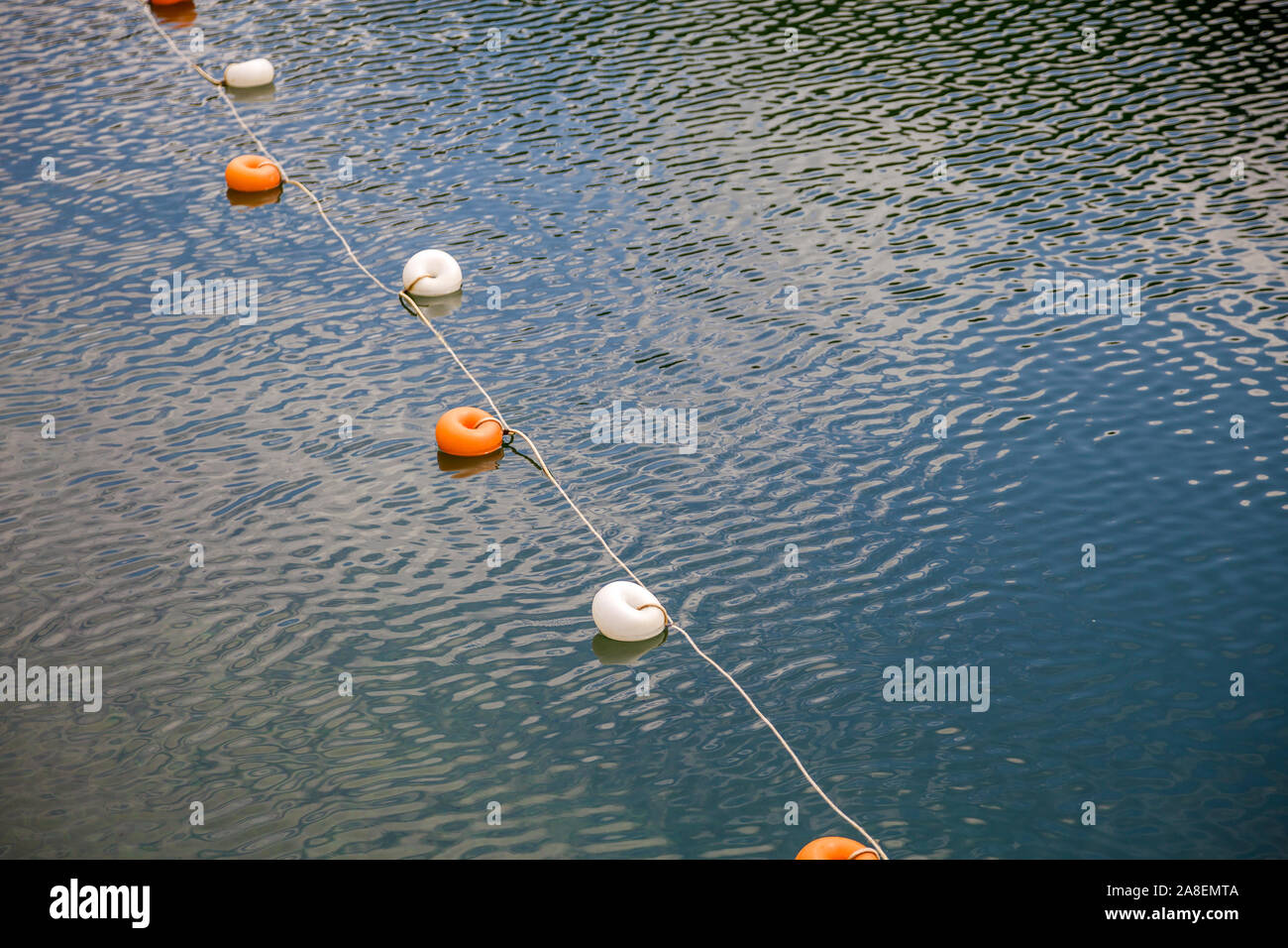 Rope with white and yellow restriction markers on water surface for ...