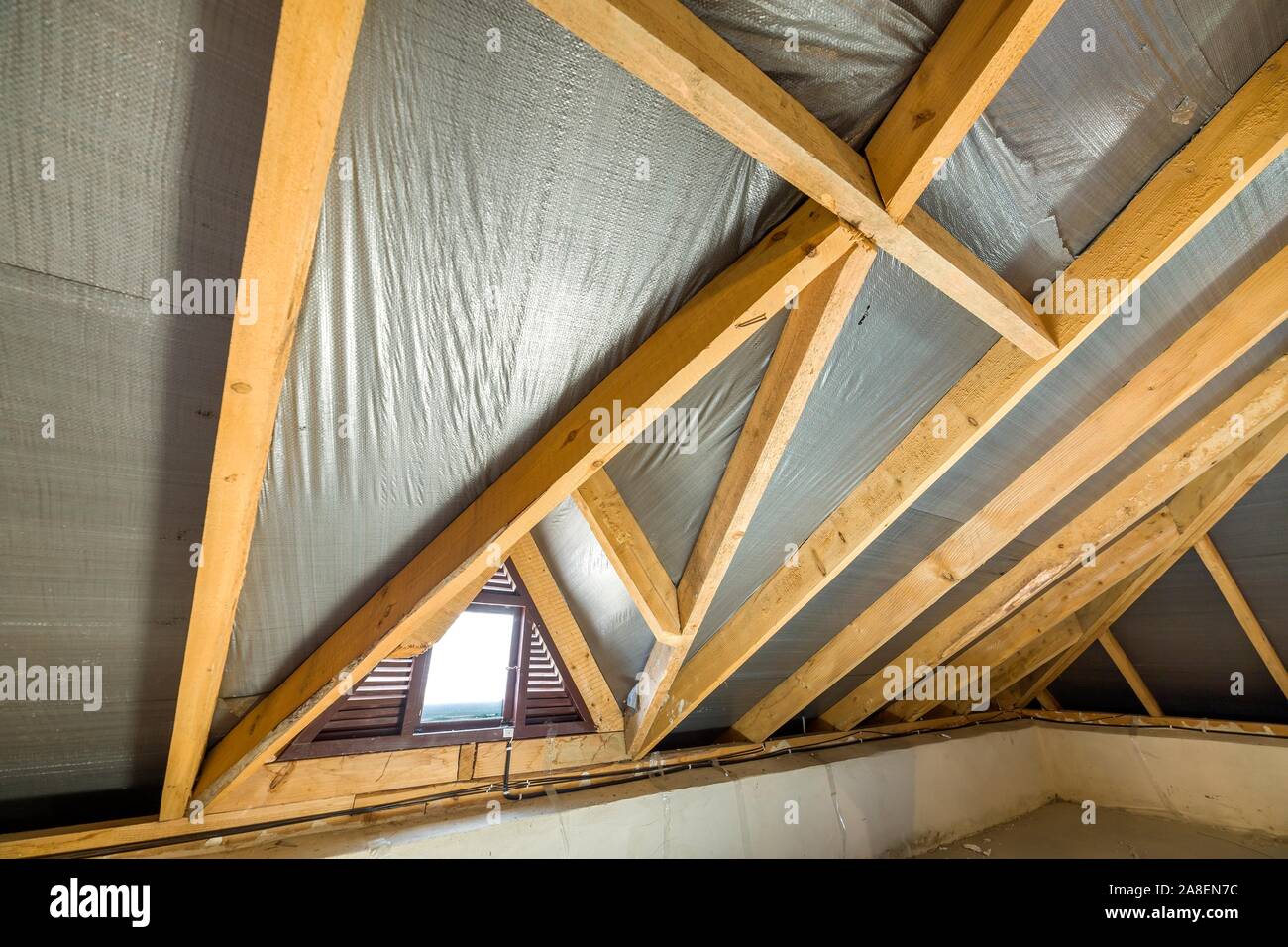 Attic of a building with wooden beams of a roof structure and a small ...