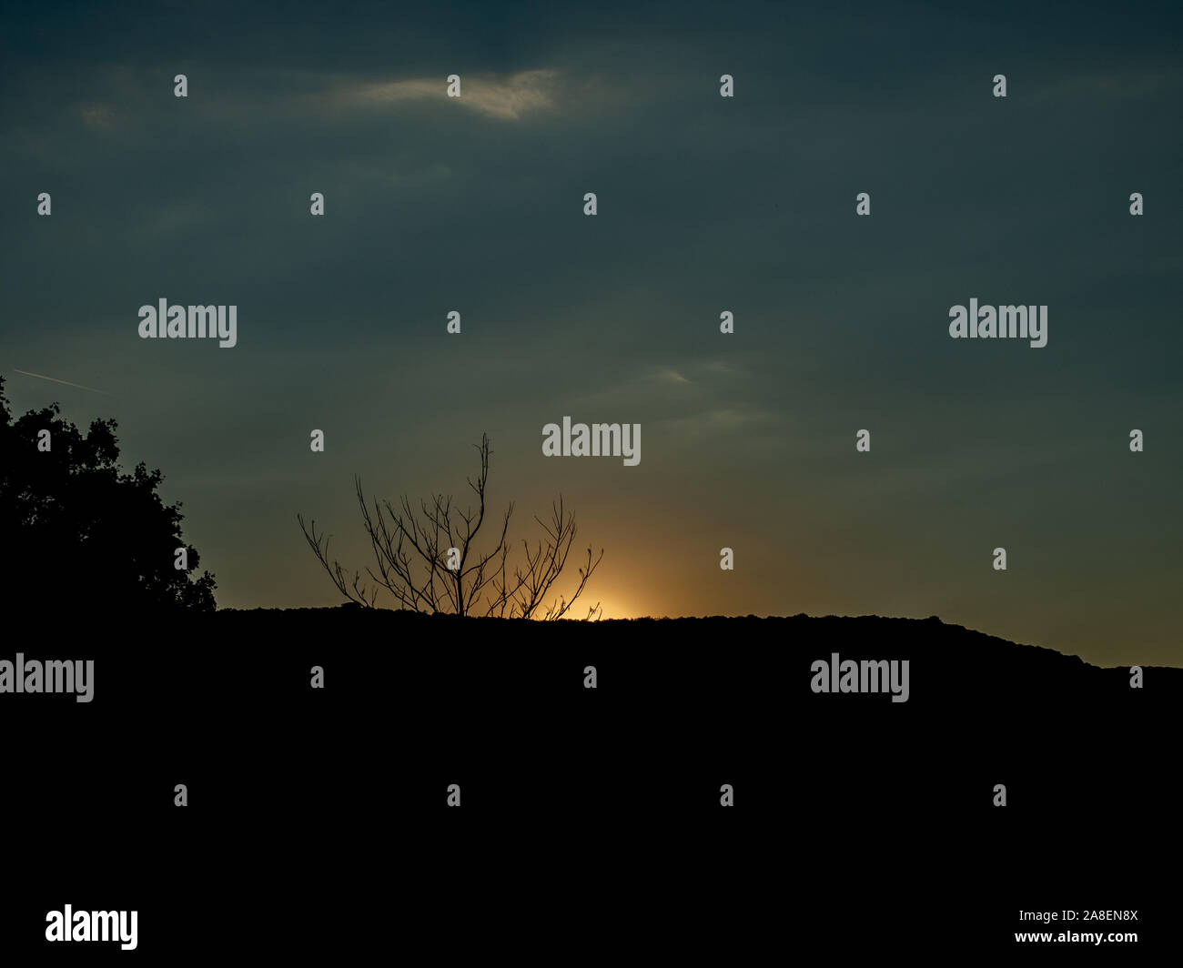 Sunset behind hills and bushes Stock Photo - Alamy