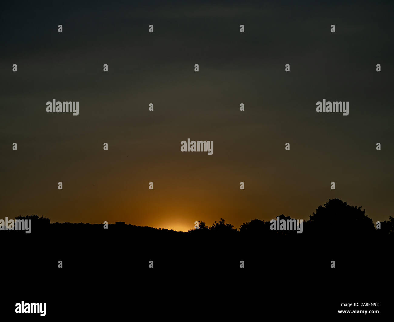 Sunset behind hills and bushes Stock Photo - Alamy