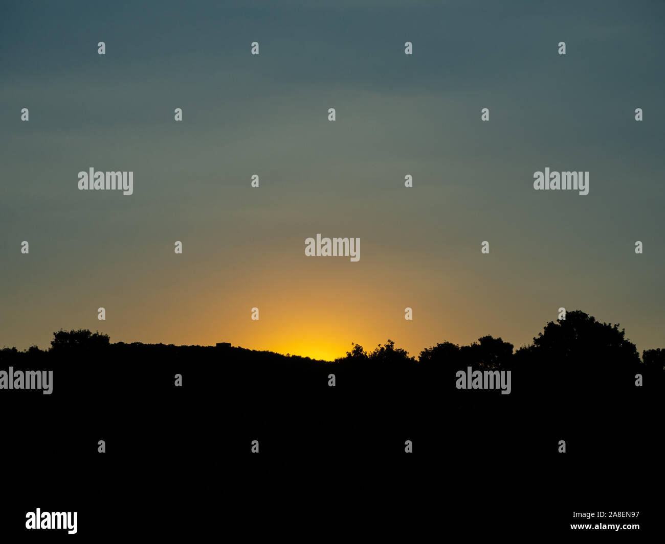 Sunset behind hills and bushes Stock Photo - Alamy