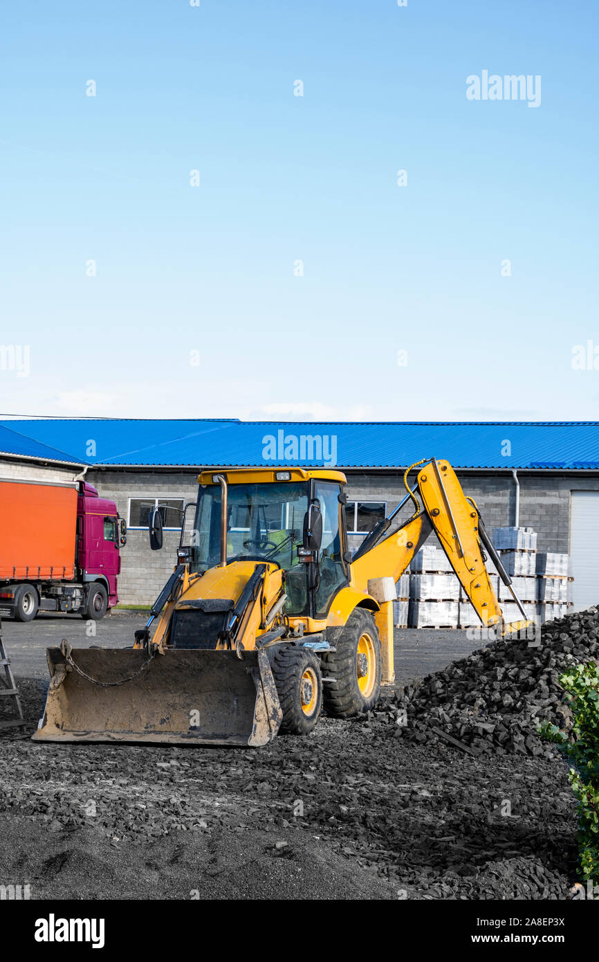 The yellow all-wheel drive backhoe loader stands on the yard ready for ...