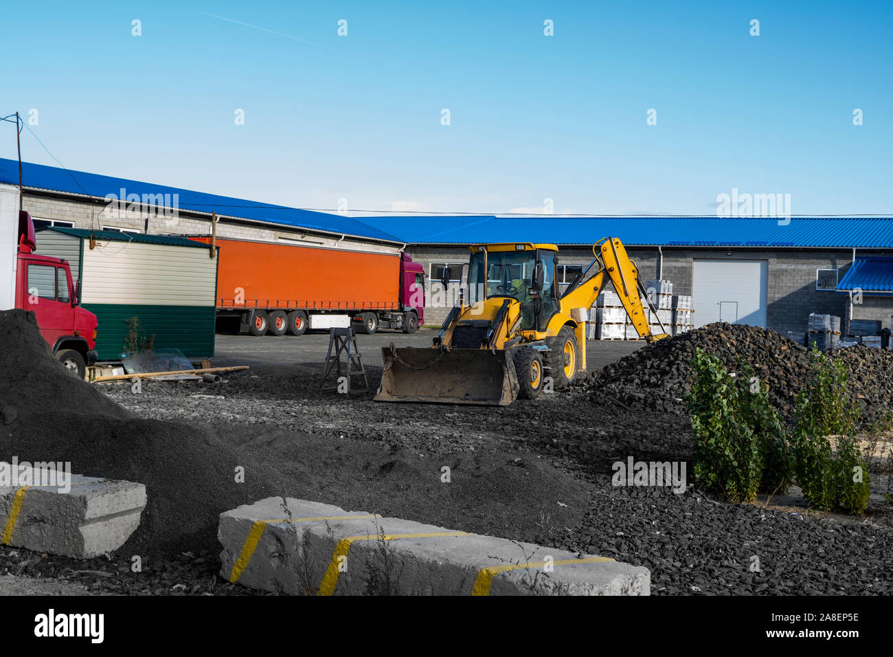 The yellow all-wheel drive backhoe loader stands on the yard ready for ...