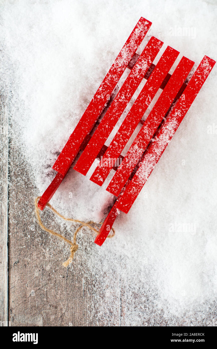 Top view of a red sledge covered with snowflakes in snow and on brown ...