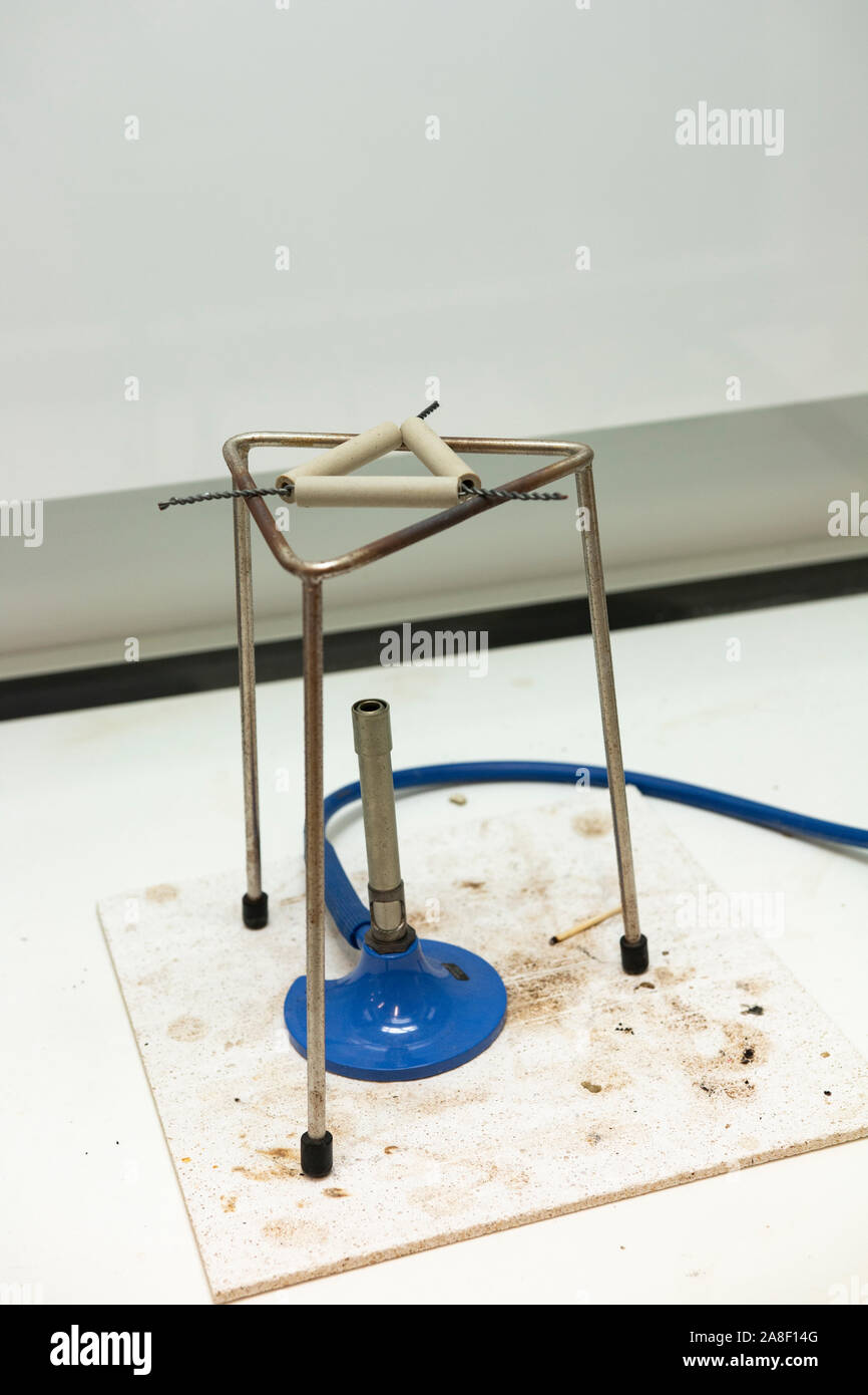 Bunsen burner with tripod and pipe clay triangle in a lab workbench in ...