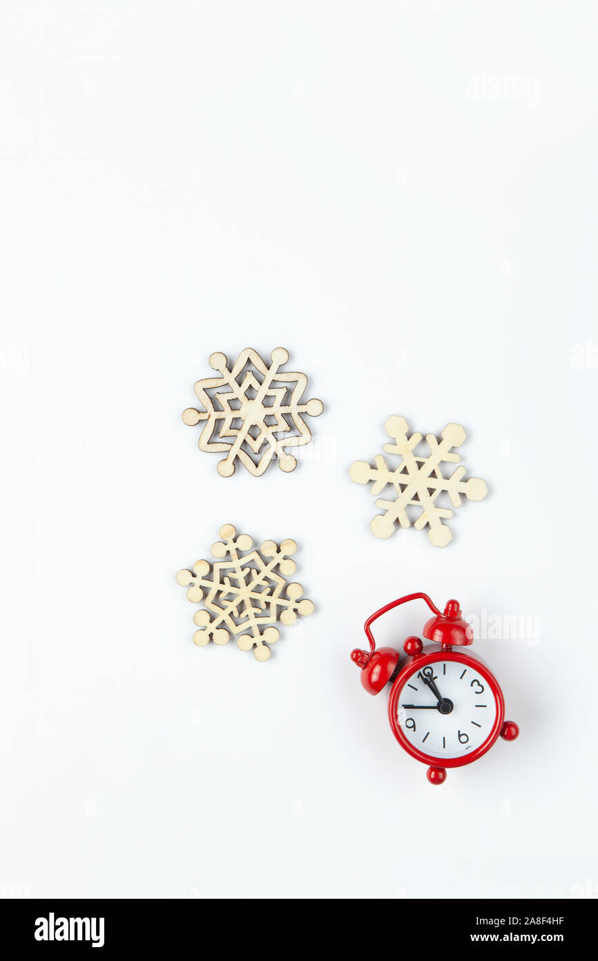 Simple Christmas composition. Small analog red clock, wooden snowflakes ...