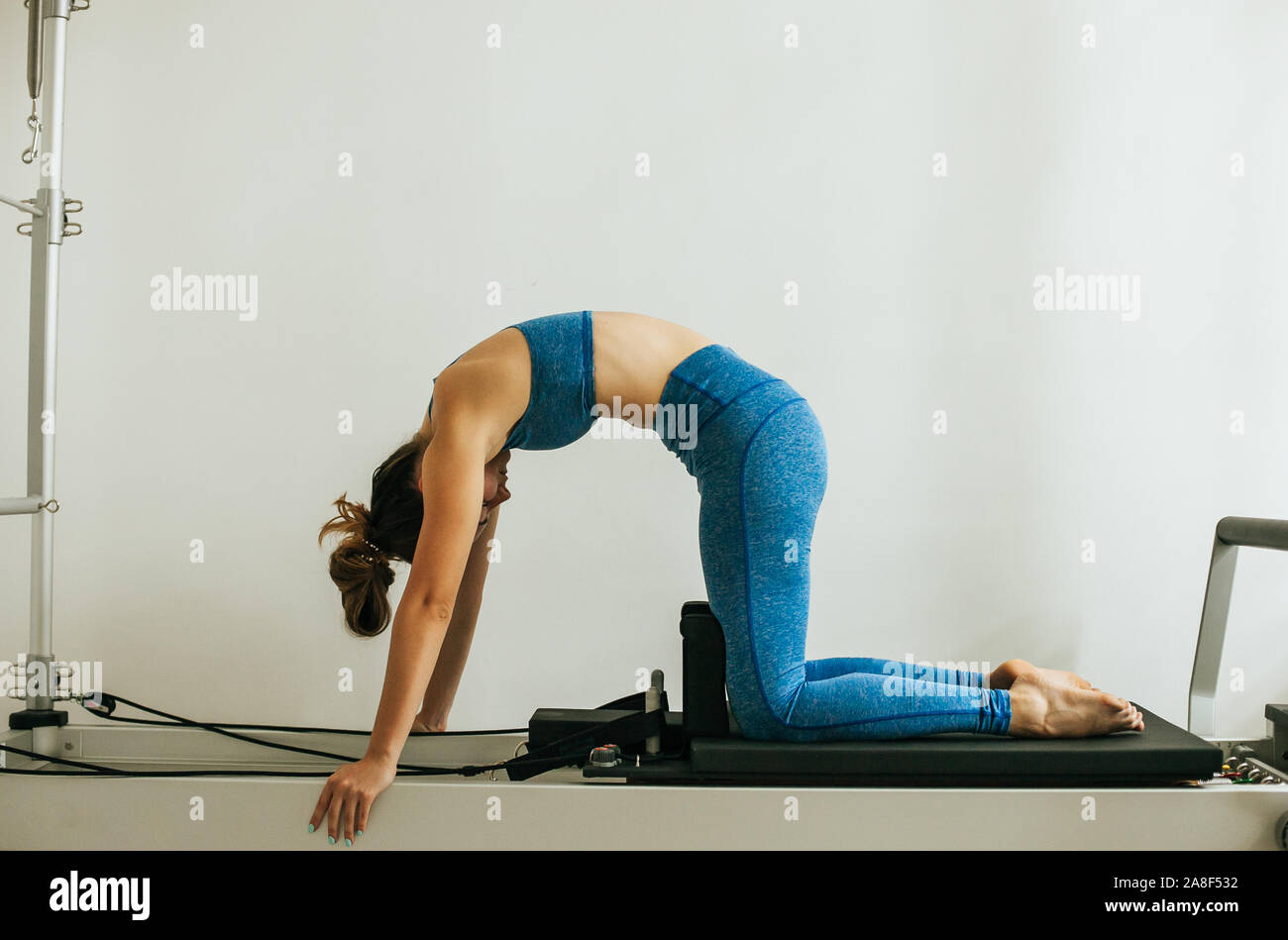 Woman performing Pilates exercise using a Cadillac or Trapeze table ...