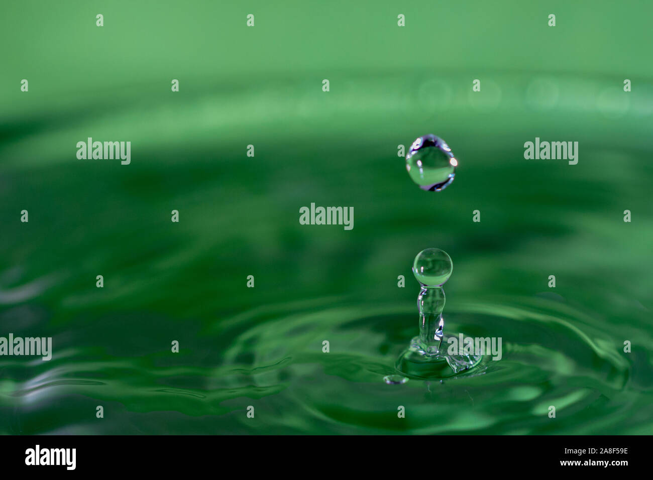 water drop splash in a green colored glass Stock Photo - Alamy