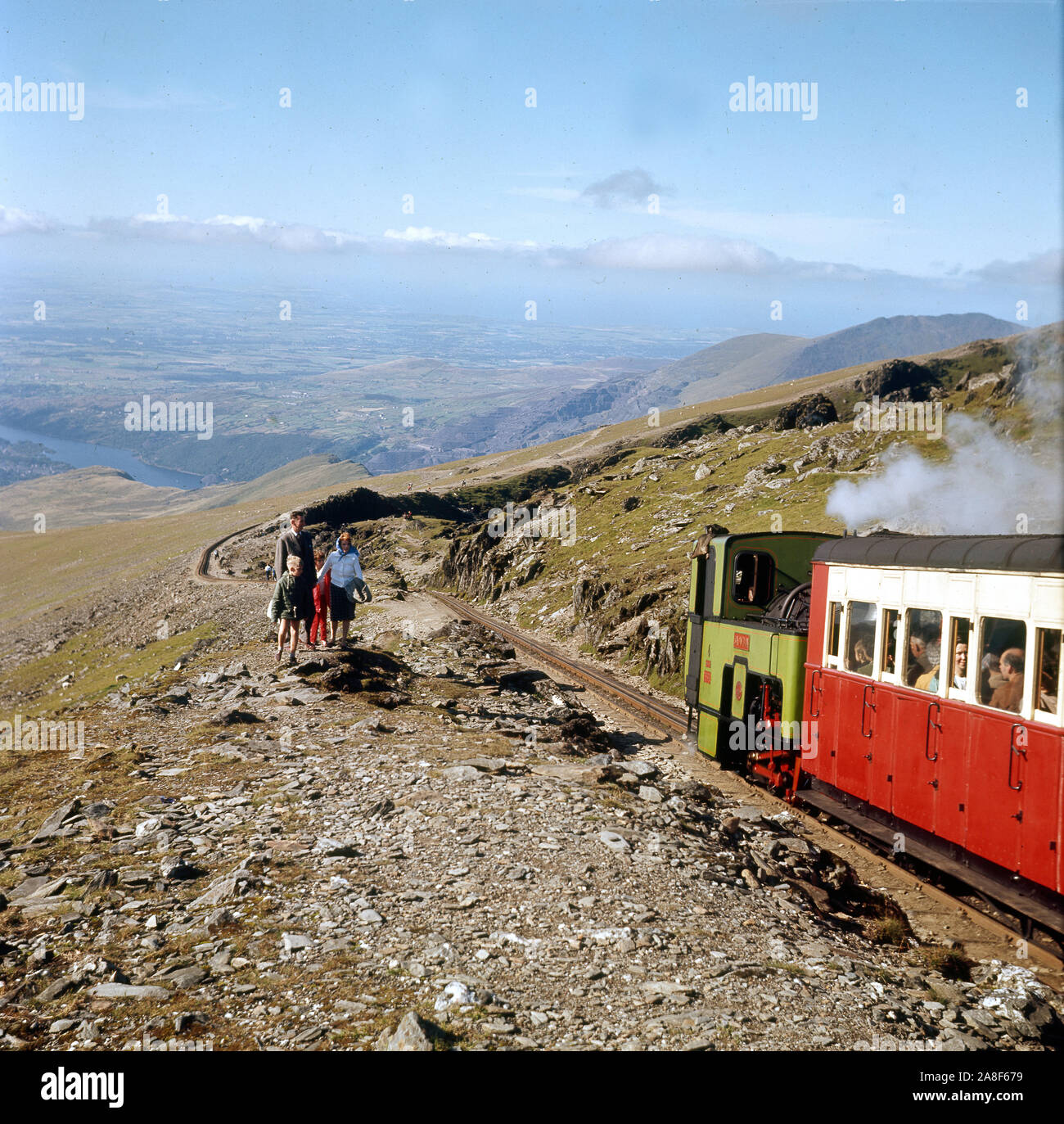 Railway train on Mount Snowdon Mountain Railway line and people walking ...