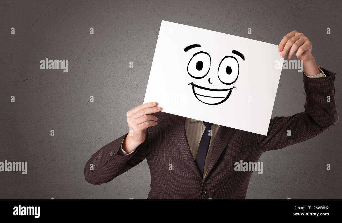 Young student holding a paper with laughing emoticon in front of his ...