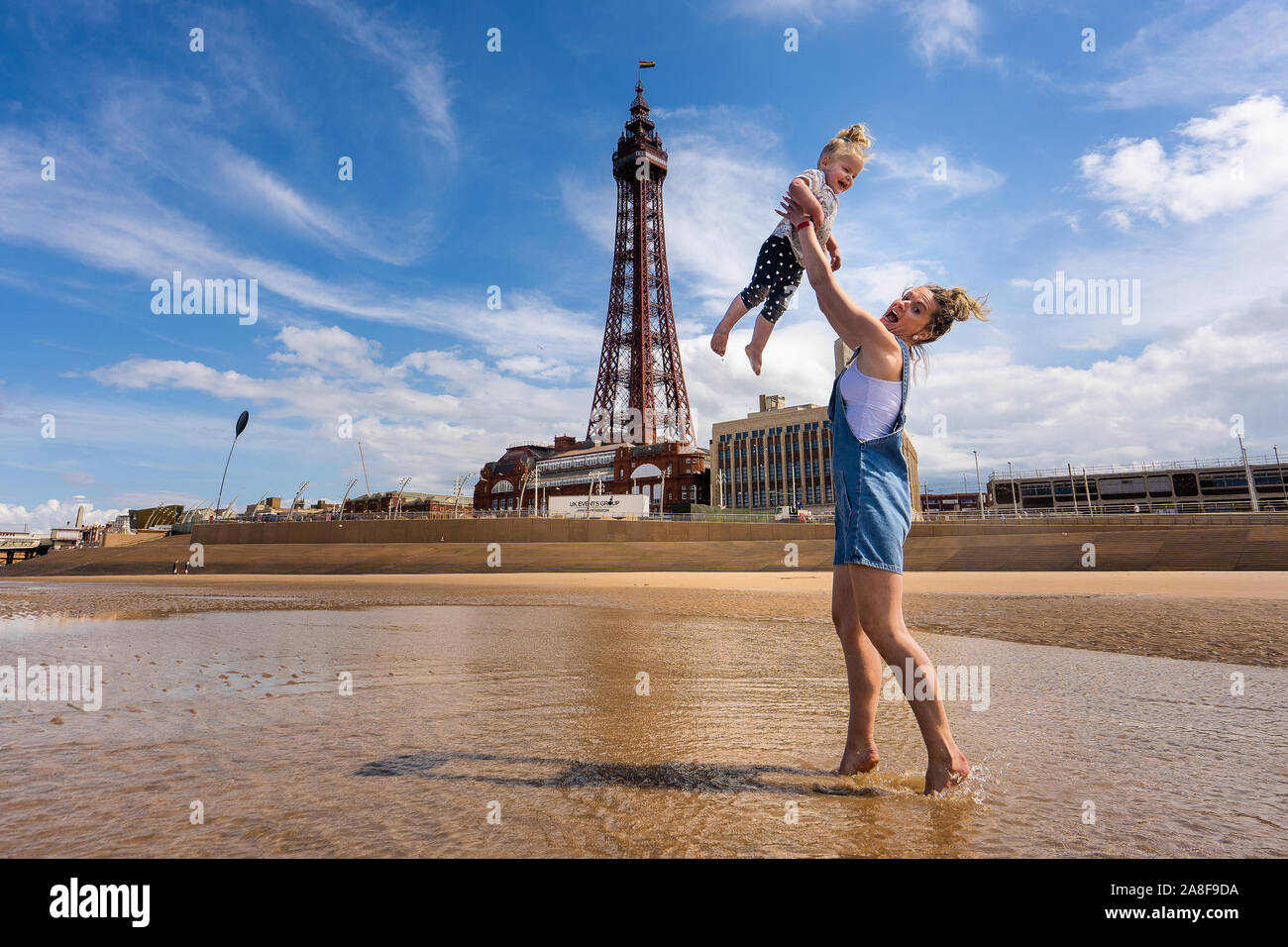 A pretty young mother holds her cute toddle daughter up in the air on ...