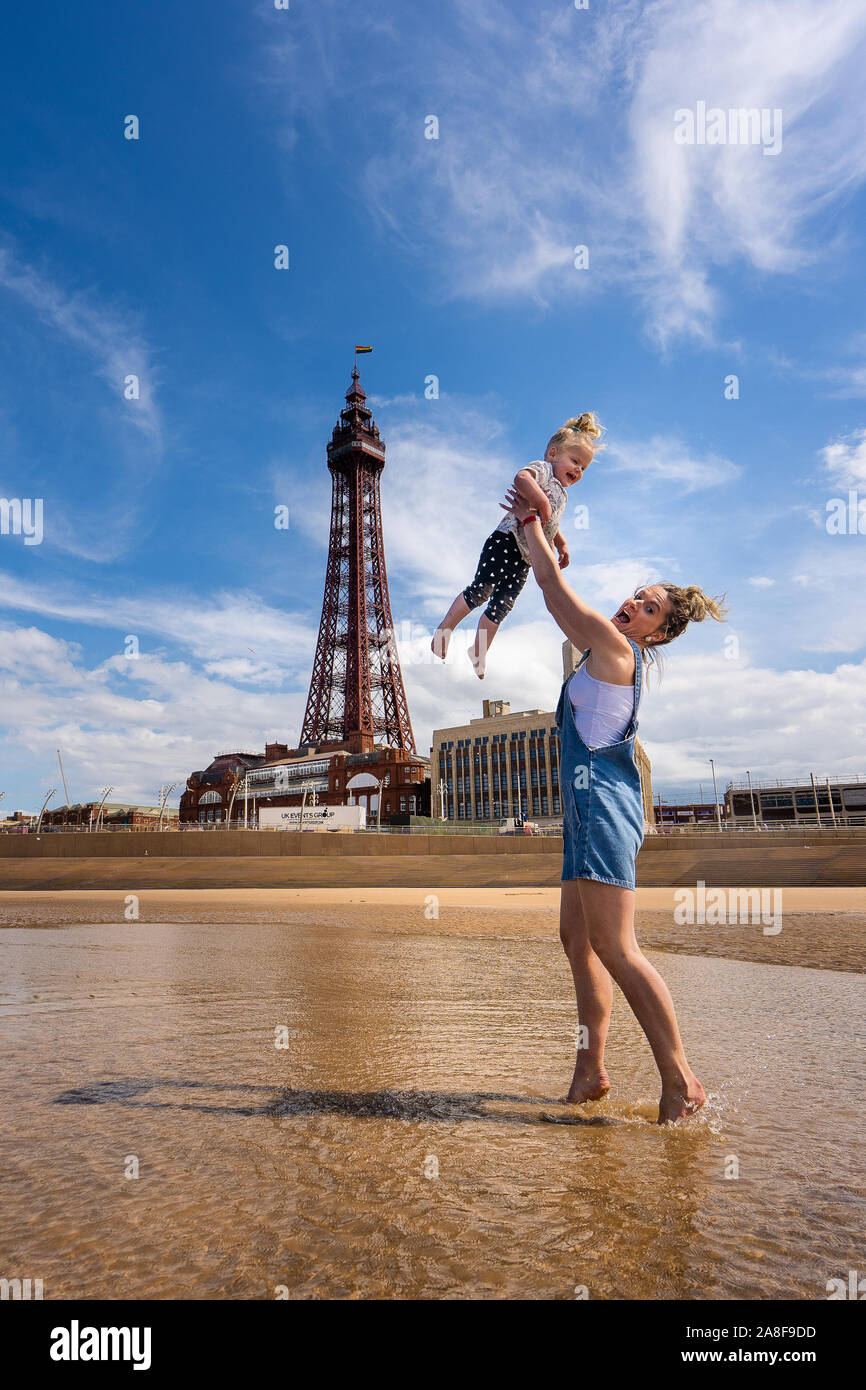 A pretty young mother holds her cute toddle daughter up in the air on ...