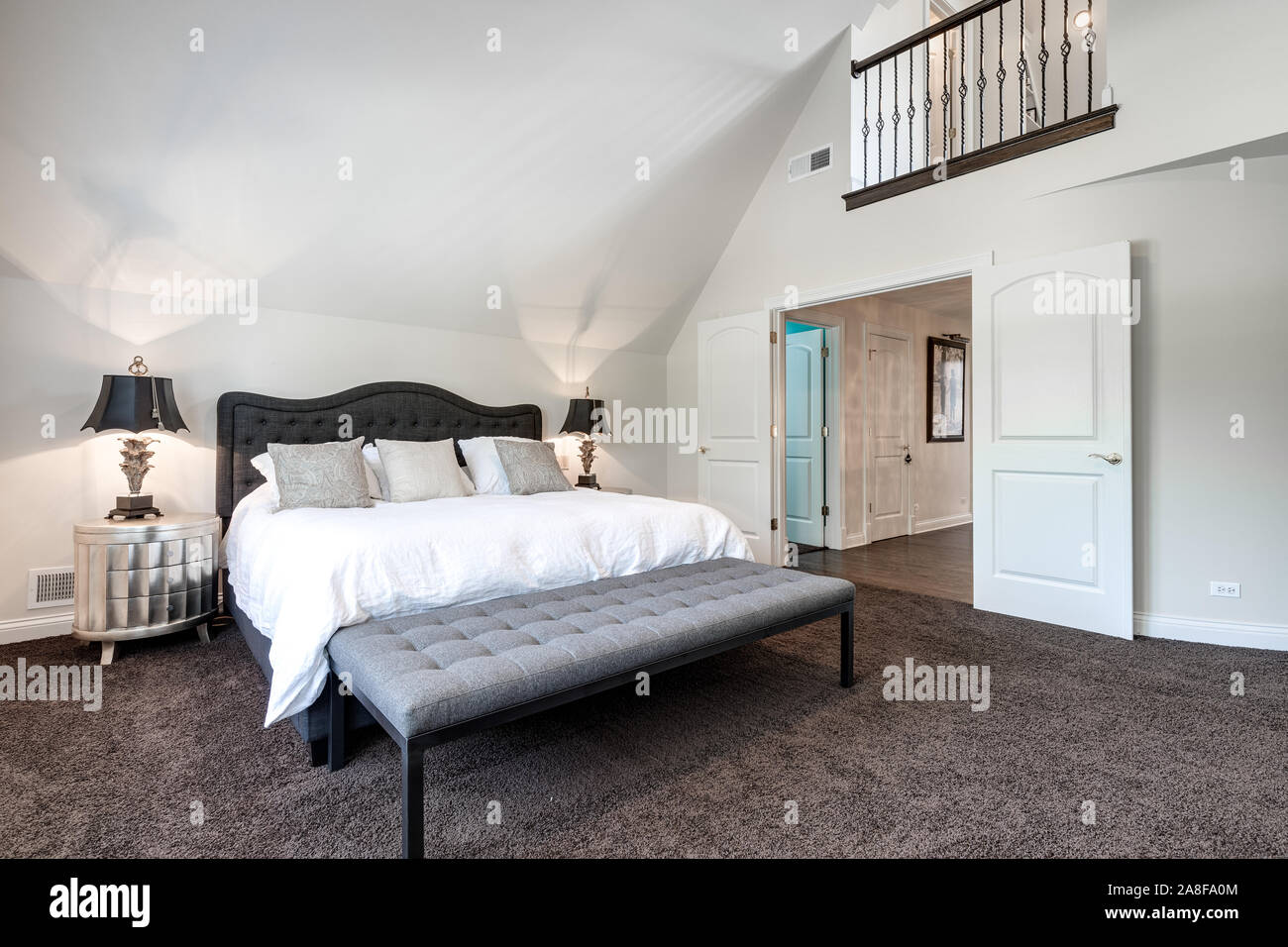 A large luxurious bedroom with double doors and a loft looking down ...