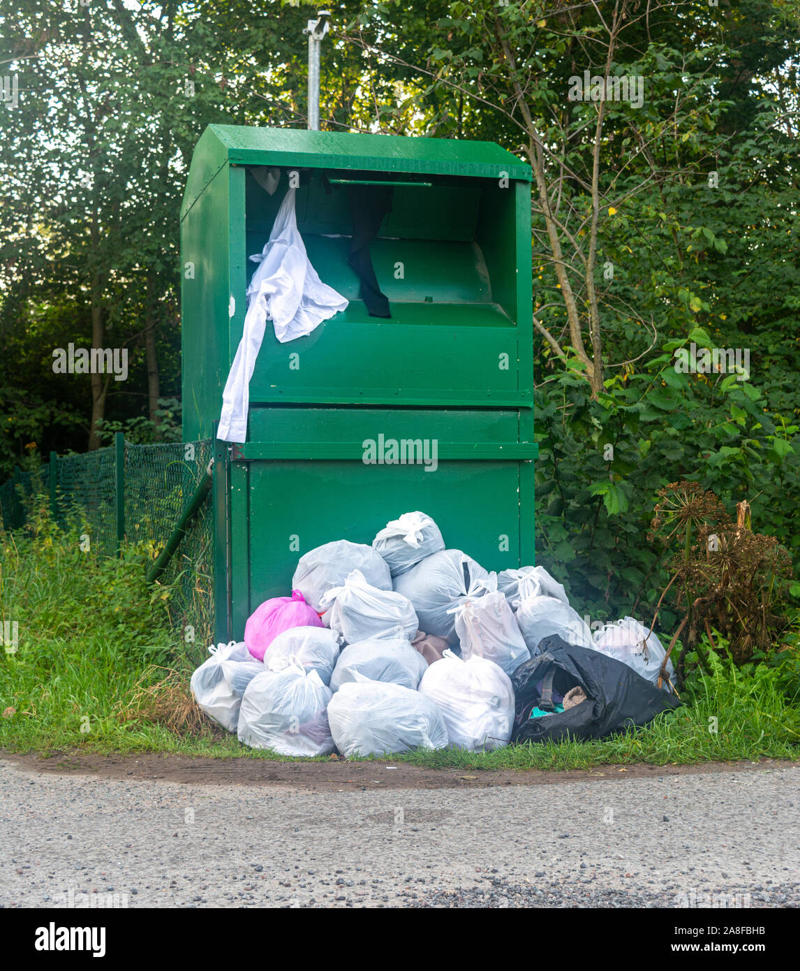 green container for clothes, bags of clothes on the street closeup ...