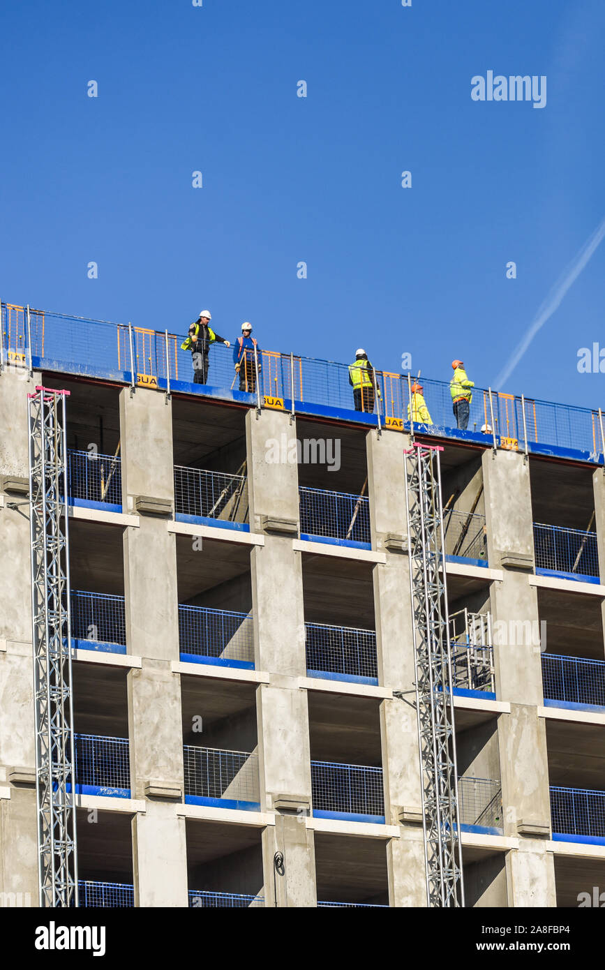 Workmen stand on the roof of a huge high rise Hilton Hotel development ...