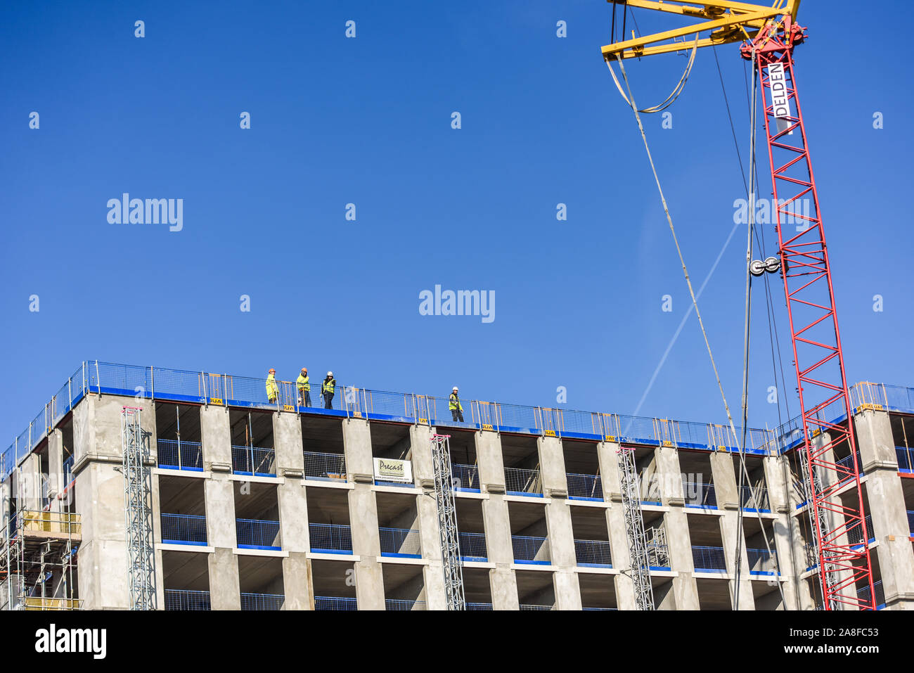 Workmen stand on the roof of a huge high rise Hilton Hotel development ...
