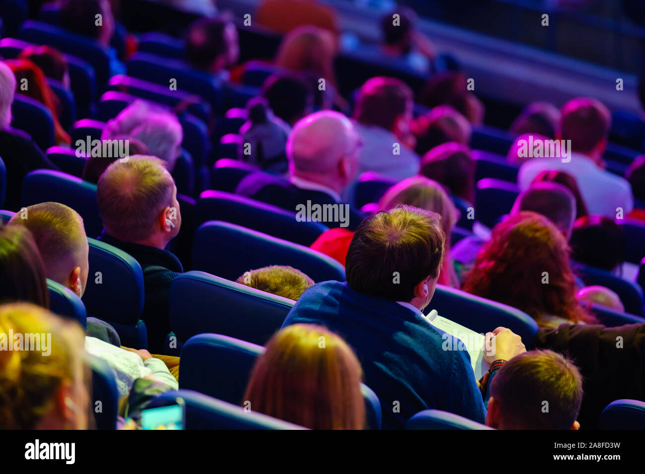 Business conference attendees sit and listen to lecturer, rear top view ...