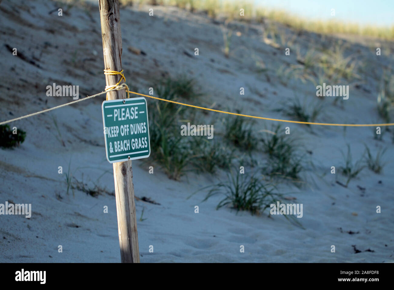 Roped off area with posted warning sign marking protected sand dunes ...
