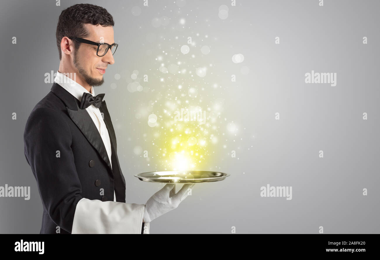 Elegant young waiter serving mysterious light on tray Stock Photo - Alamy