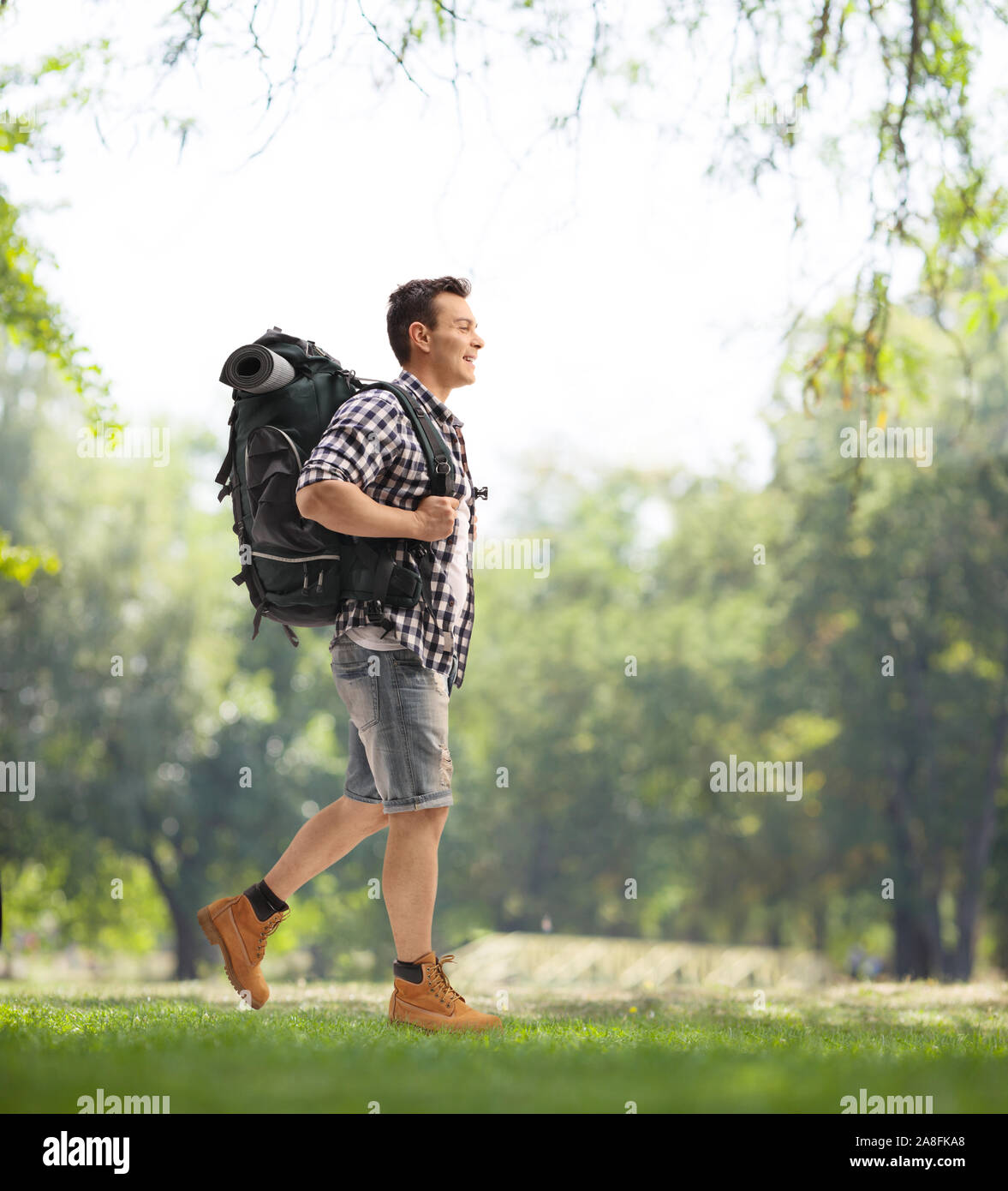 Full length profile shot of a young male hiker with a backpack walking ...