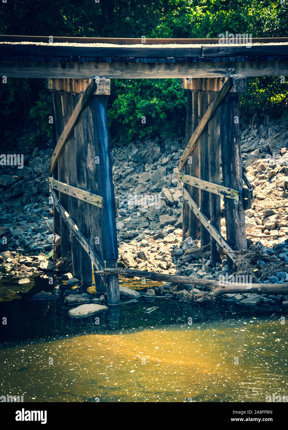 Railroad track across a rickety wooden trestle with stagnant water ...