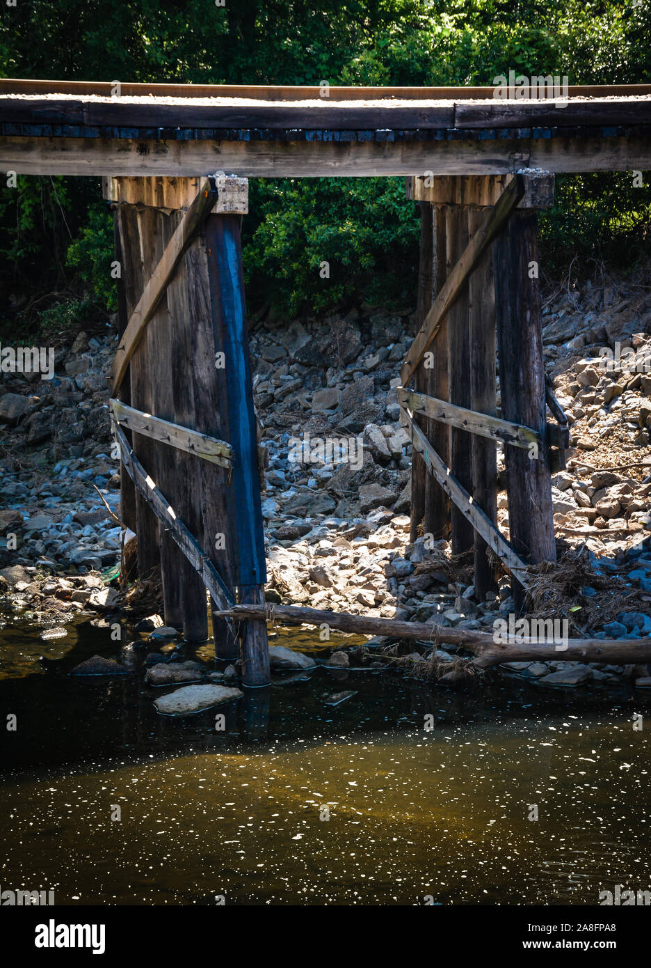Railroad track across a rickety wooden trestle with stagnant water ...