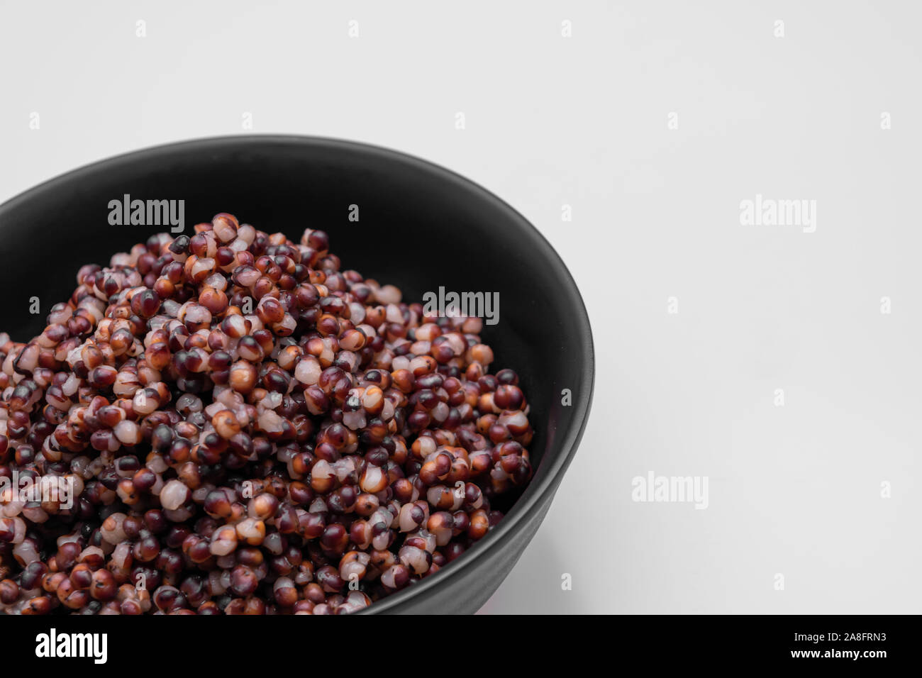 Cooked Sorghum (also known as sorgo) in a back bowl, isolated Stock ...